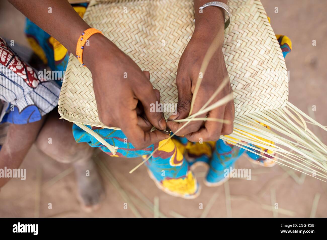A Fulani woman weaves matts and fans from dried palm fronds by hand for ...