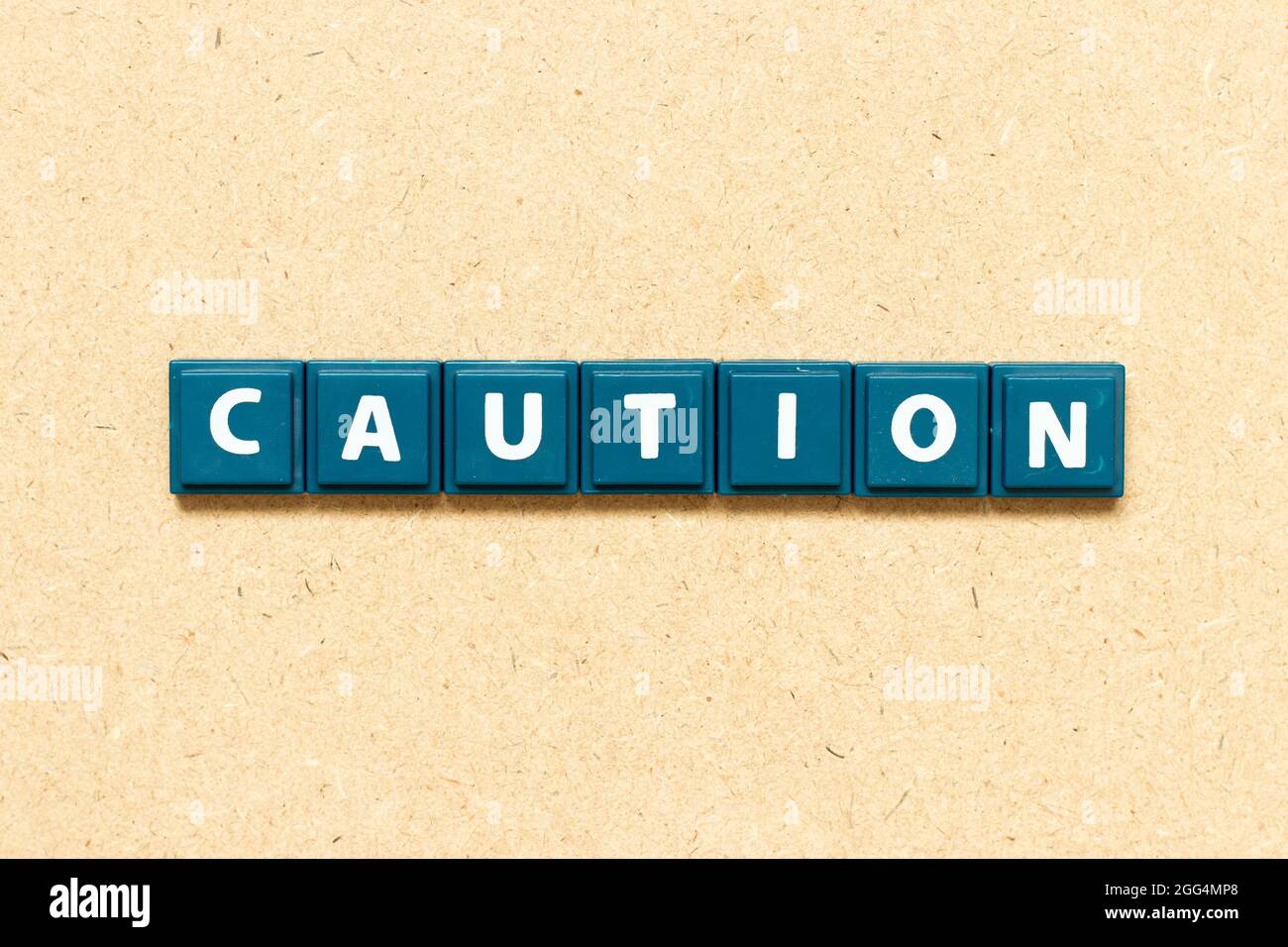 Tile alphabet letter in word caution on wood background Stock Photo - Alamy