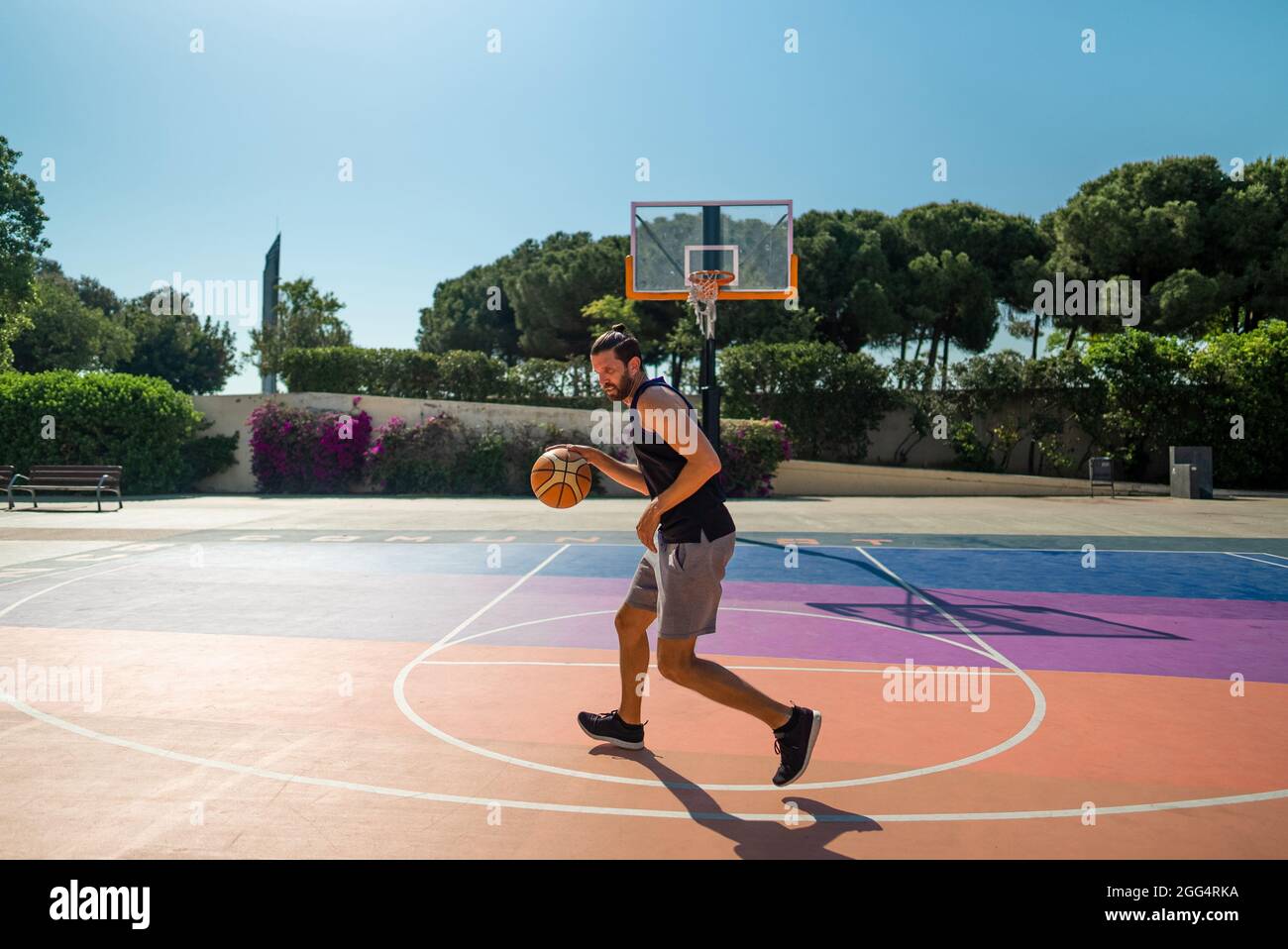A male basketball player trains himself on a basketball court with a ...