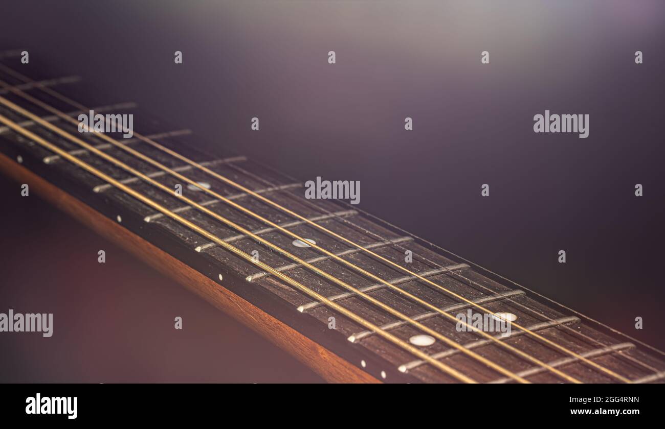 Part of an acoustic guitar, guitar fretboard with strings on a black ...