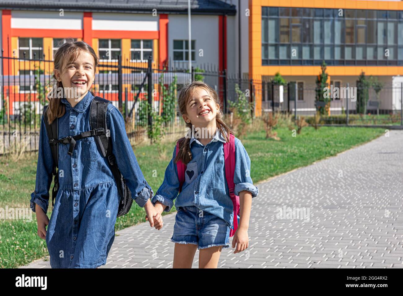 Pupils of primary school. Girls with backpacks near school outdoors ...