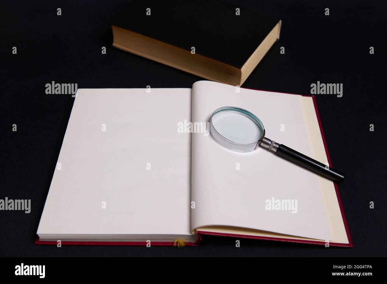 A magnifying glass, loupe, magnifier on an opened book in hard red ...