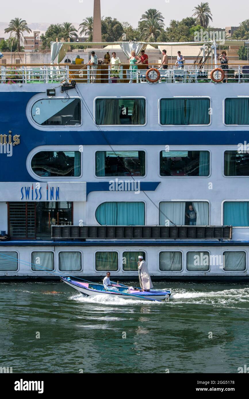 Textile salesman aboard a rowing boat being towed by a floating hotel ...