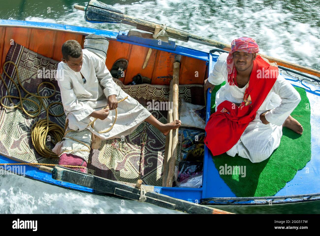 Textile salesman aboard a rowing boat being towed by a floating hotel ...