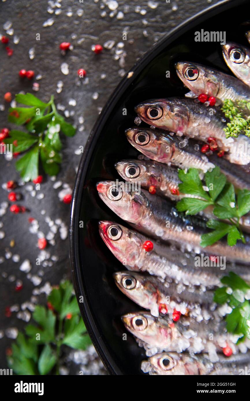 Presentation of a dish of raw anchovies on black background Stock Photo ...