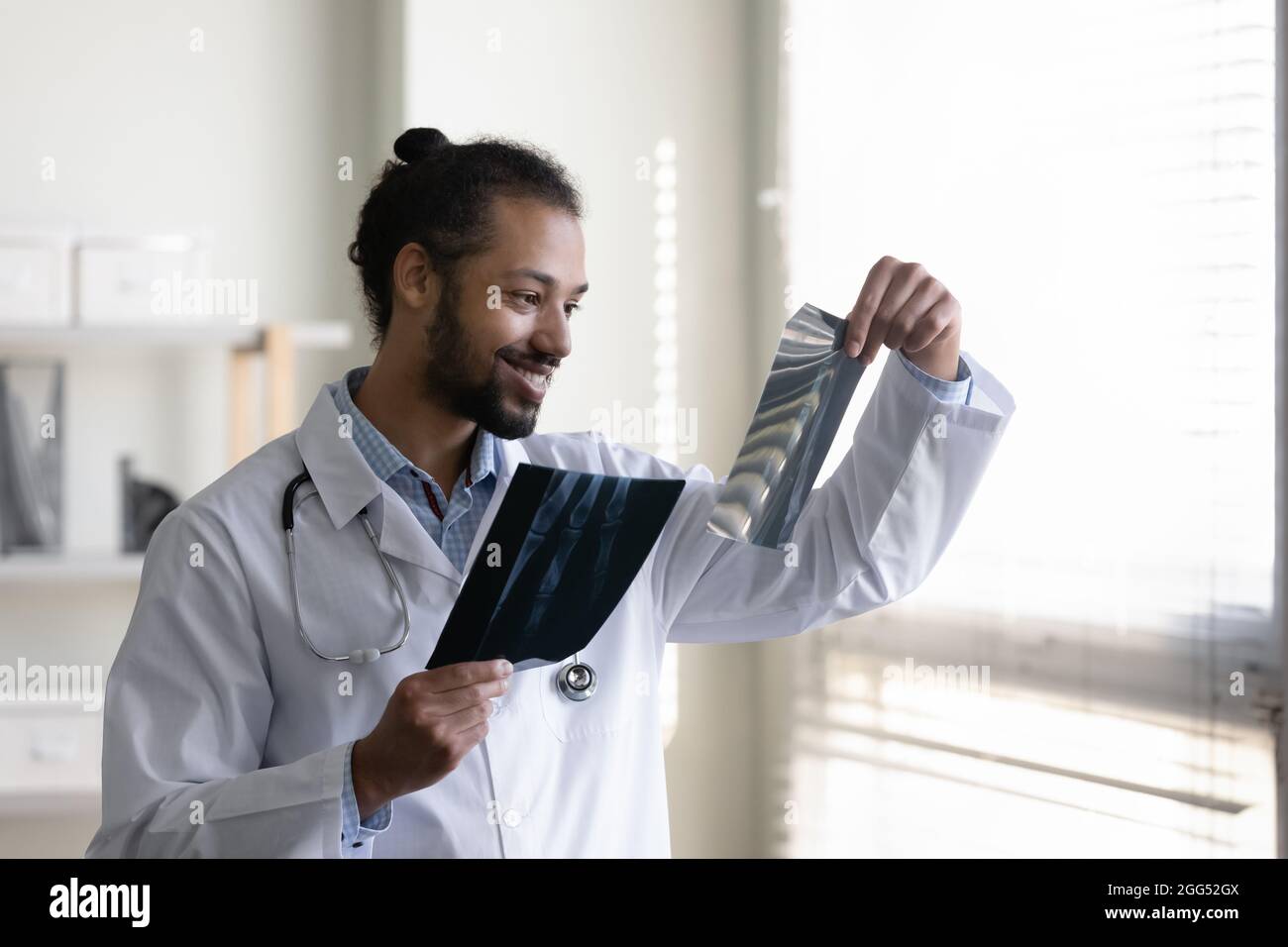 Happy young african american surgeon analyzing x-ray images Stock Photo ...