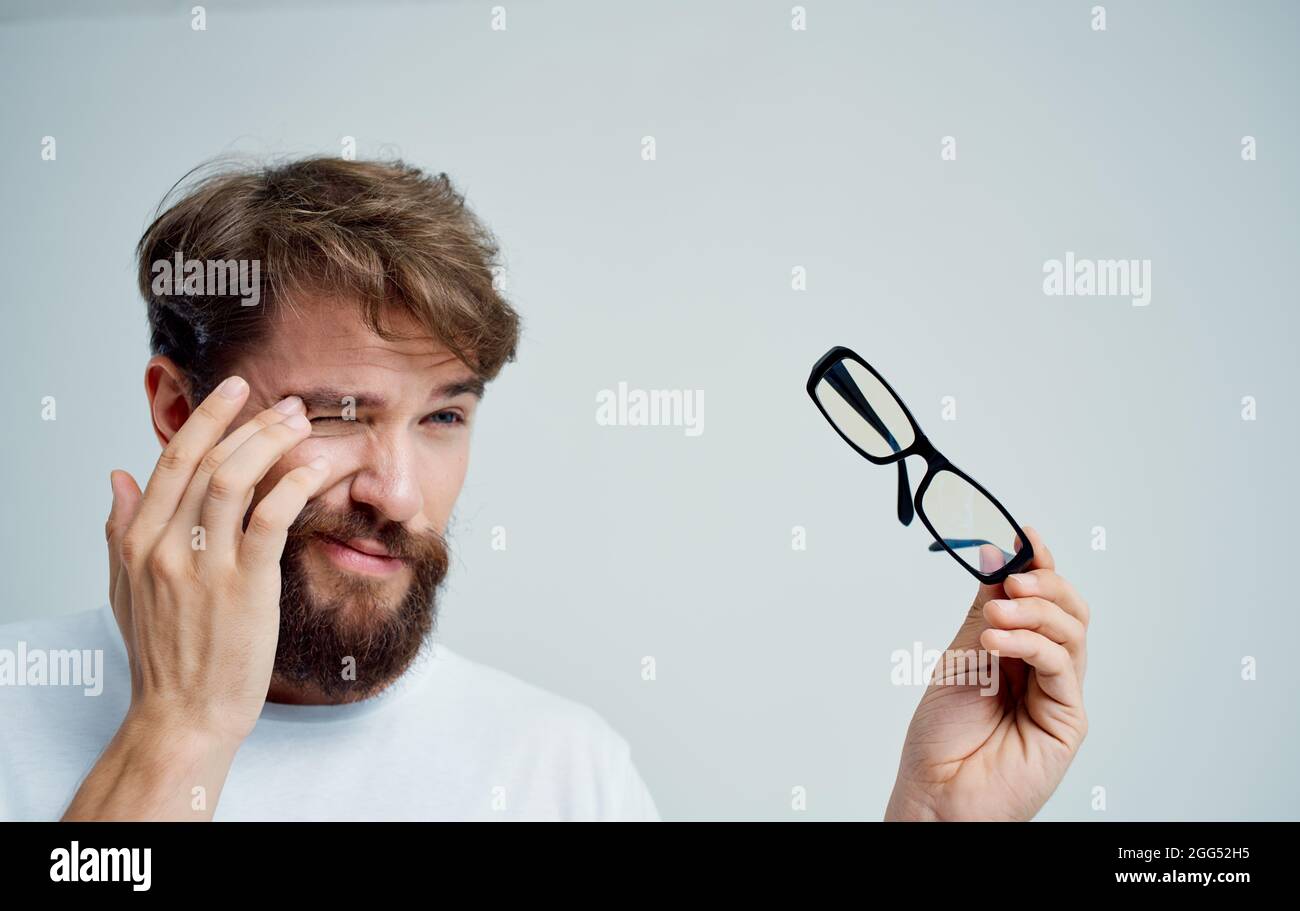 a man with poor eyesight holding glasses in his hands health problems ...