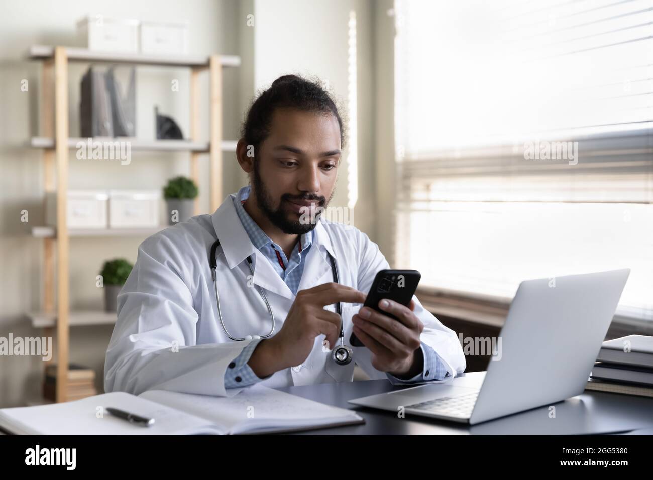 Concentrated young african american male gp doctor using cellphone ...