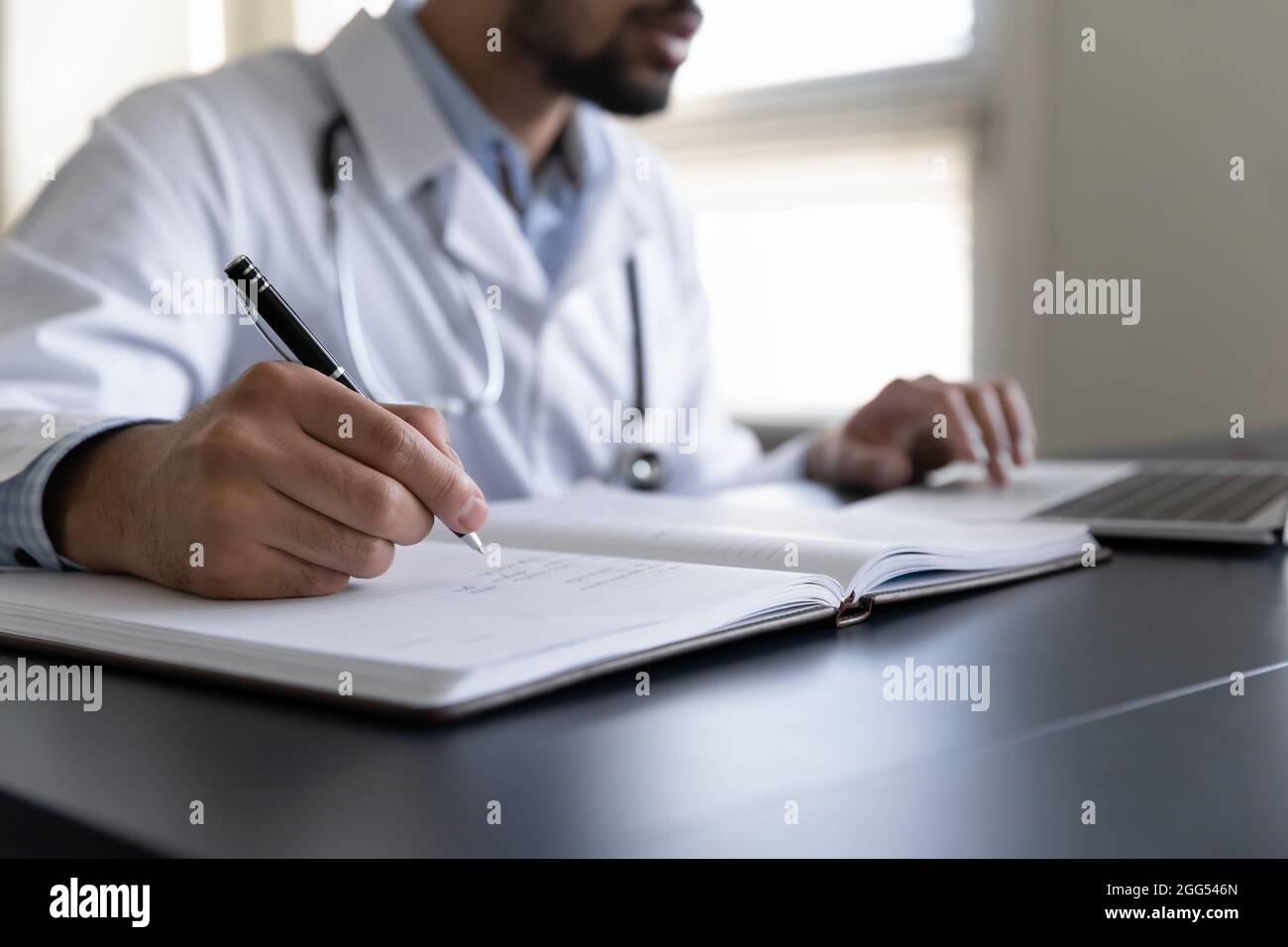 Close up cropped young african american male doctor handwriting notes ...