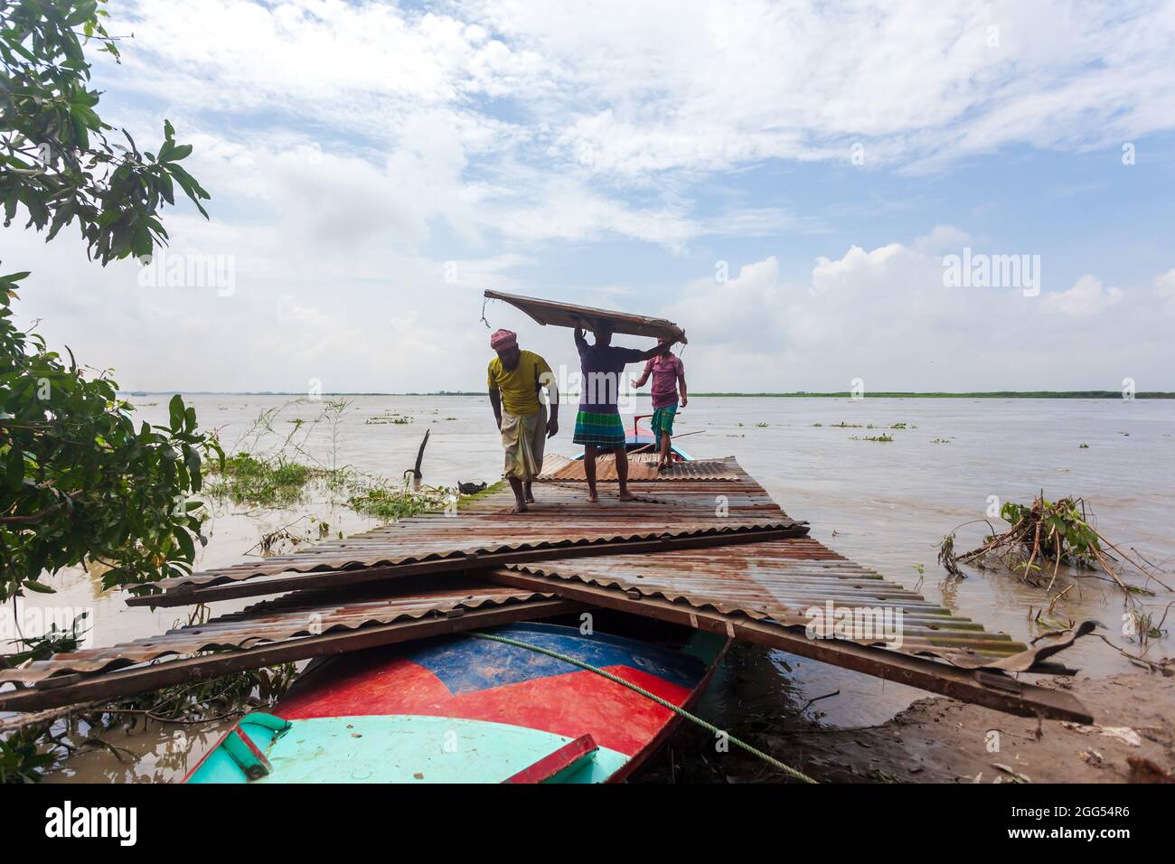 Laborers carry iron sheets from a damaged house as the erosion of the ...