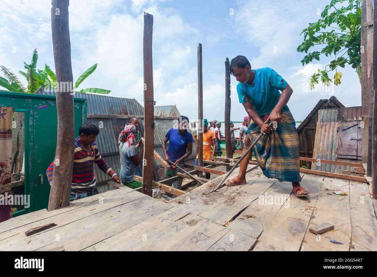 Laborers carry timbers from a damaged house as the erosion of the River ...