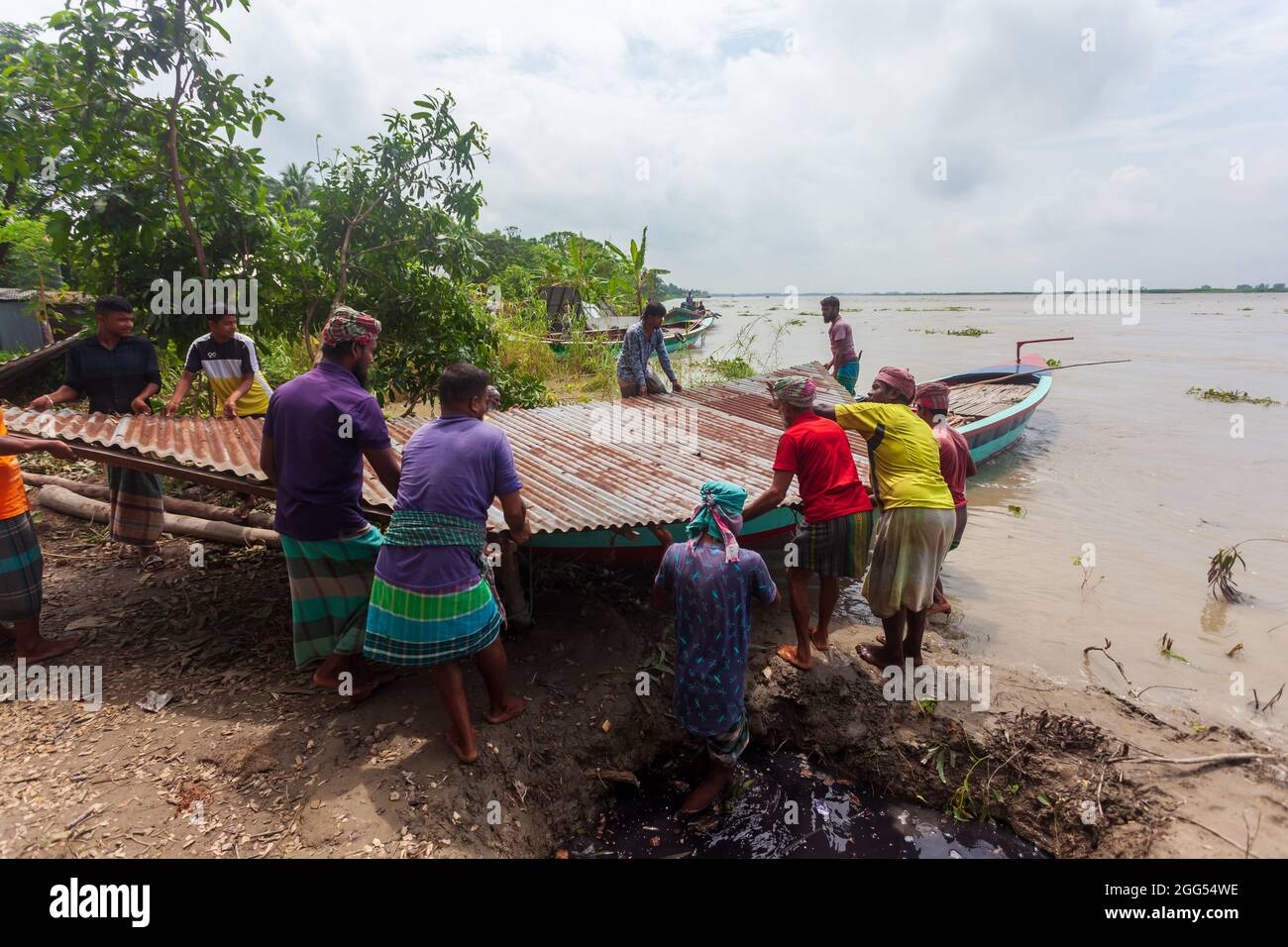 Laborers carry iron sheets from a damaged house as the erosion of the ...