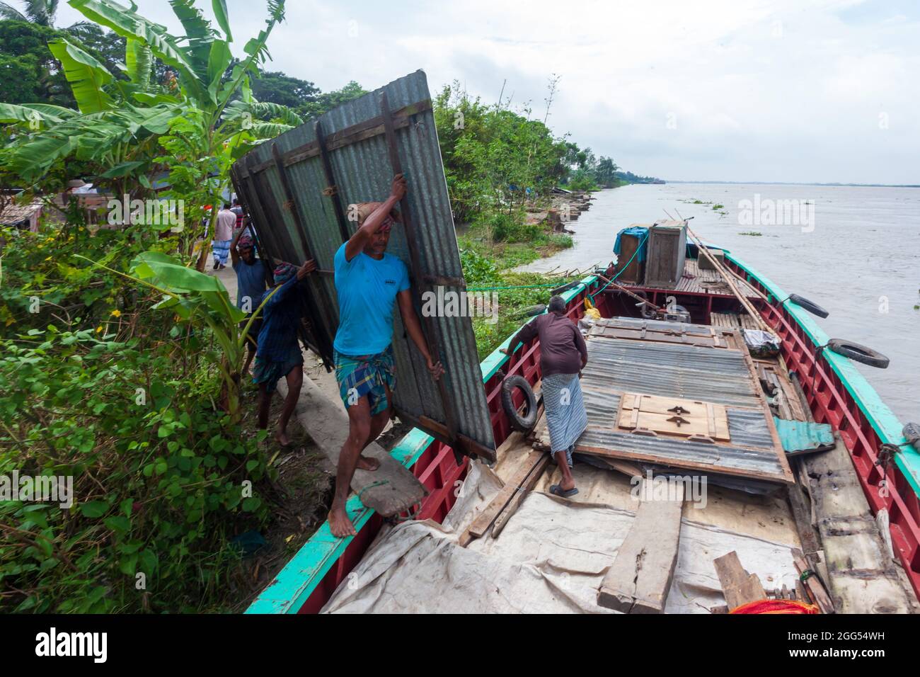Laborers carry iron sheets from a damaged house as the erosion of the ...