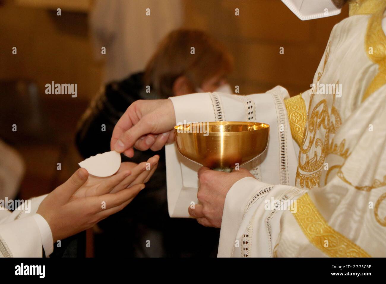Communion rite during mass in a Catholic church. Priest give host in ...