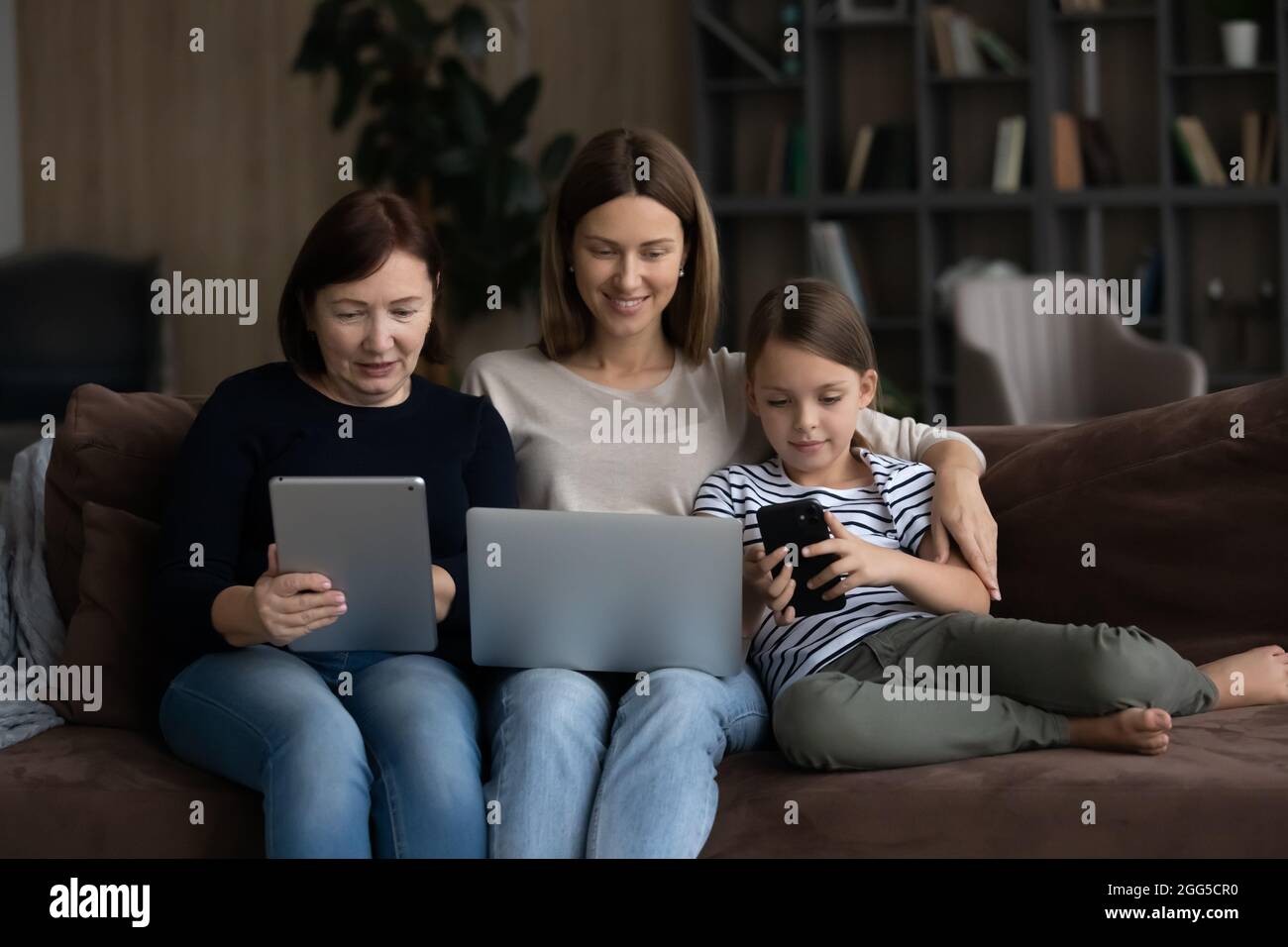 Happy three female generations family using different gadgets Stock ...