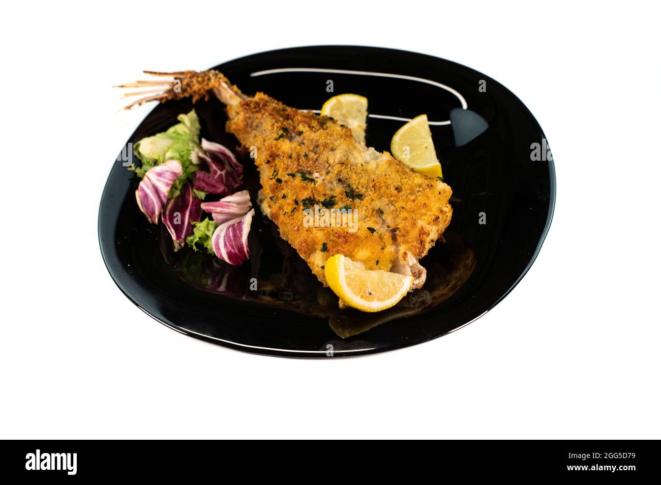 black plate with breaded monkfish on white background Stock Photo - Alamy