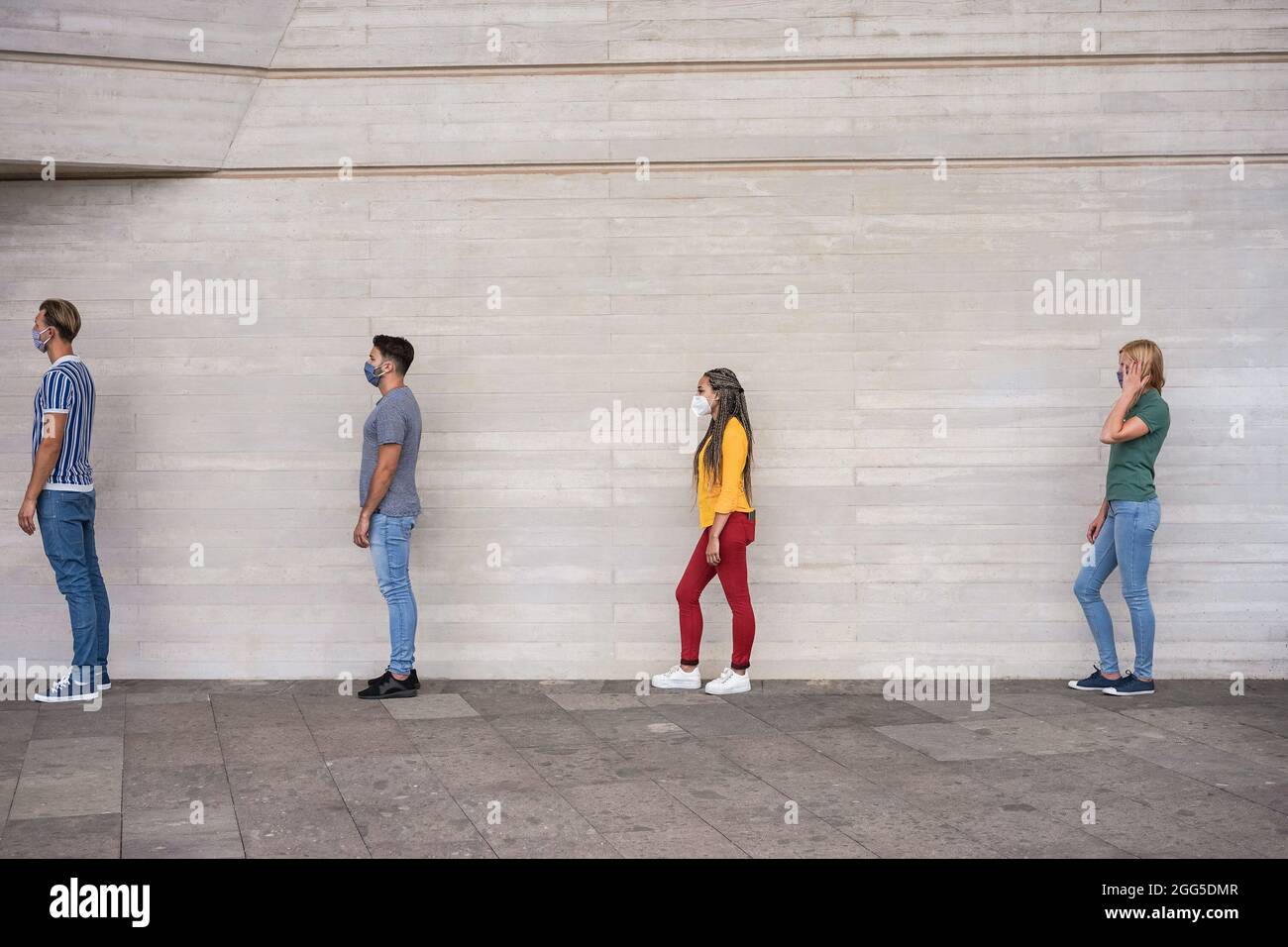 Group of young people waiting in line while keeping social distance ...