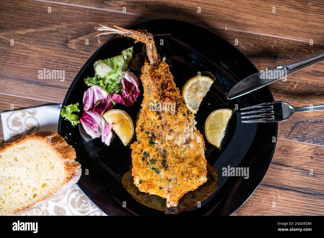 monkfish au gratin plate with composition on wooden top and wine glass ...