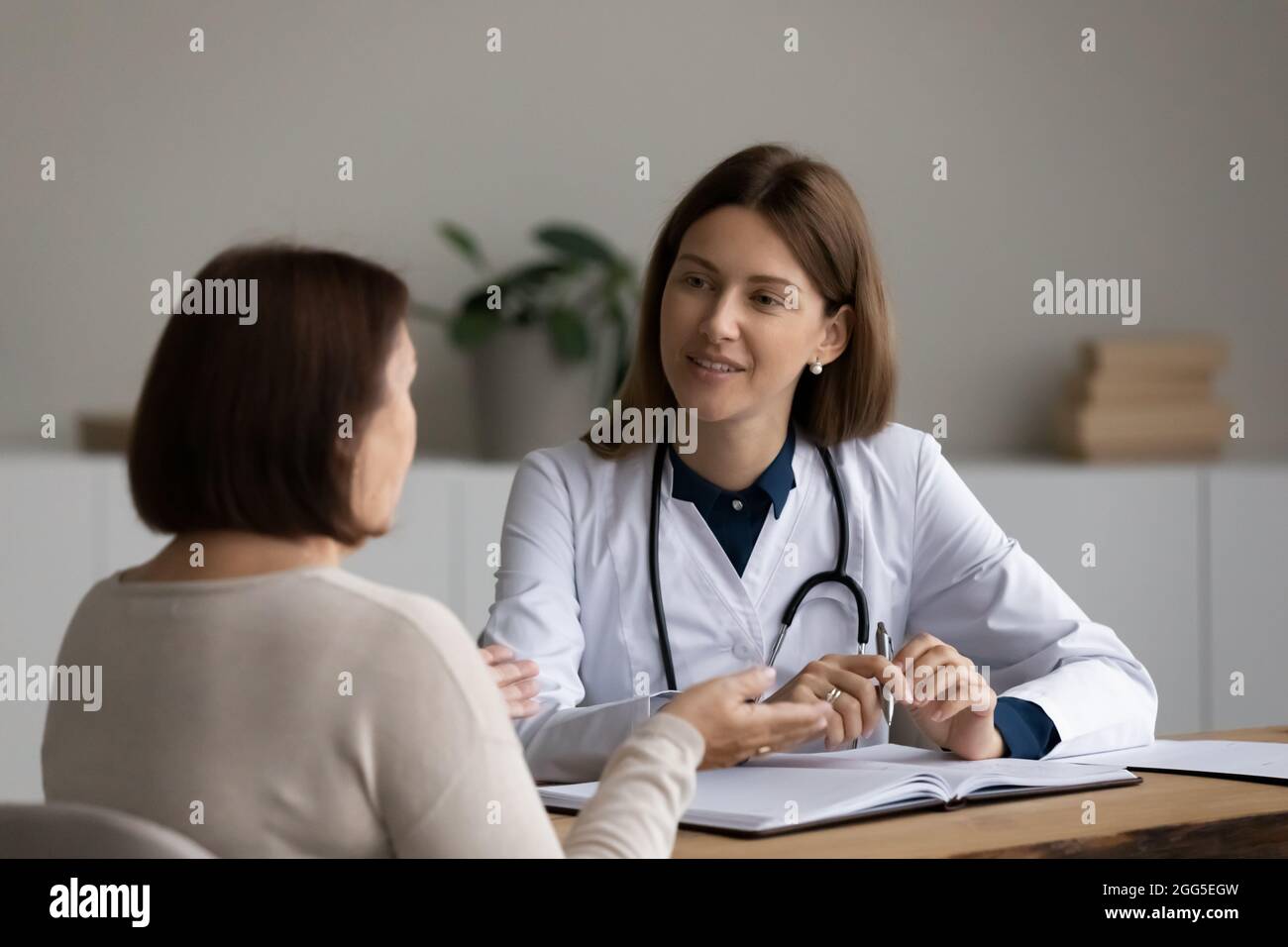 Happy young GP doctor examining older patient Stock Photo - Alamy