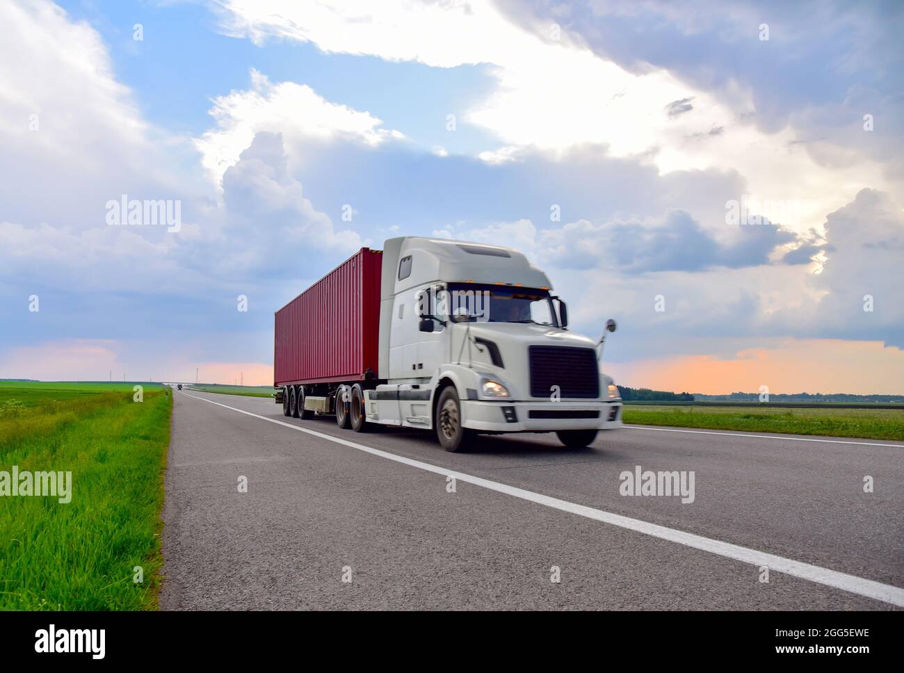 American semi truck transporting sea container on highway on sunset ...