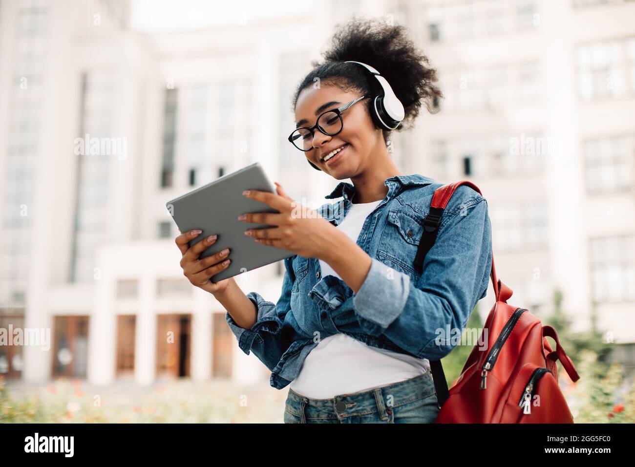Happy Black Female Student Using Tablet Computer Wearing Headphones ...
