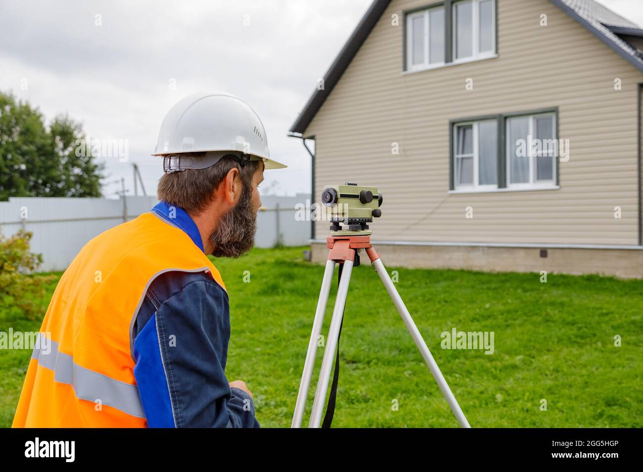 A male engineer works with the optical level on site. A builder in a ...
