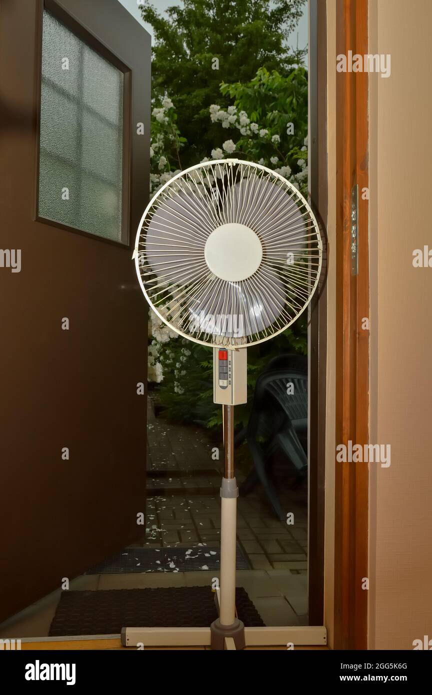 Electric floor fan stands at the door of the house for cooling in hot ...
