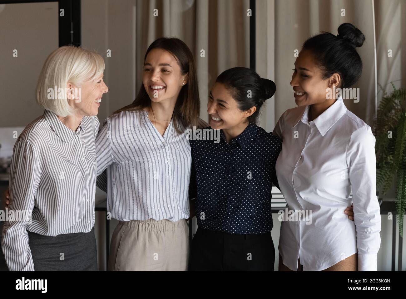 Happy diverse colleagues employees hugging, having fun, standing in ...