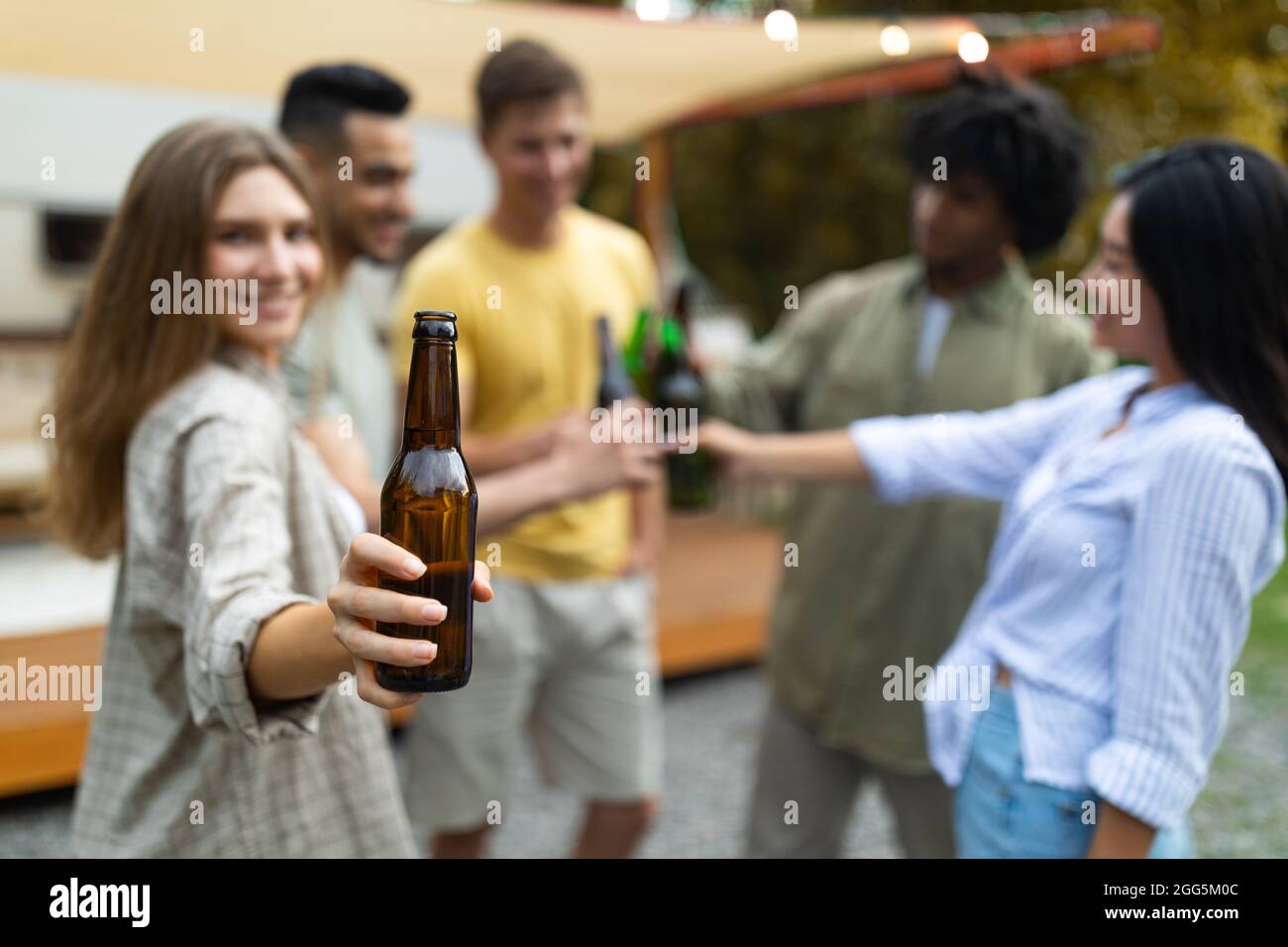 Pretty Caucasian lady with her diverse friends toasting with beer ...