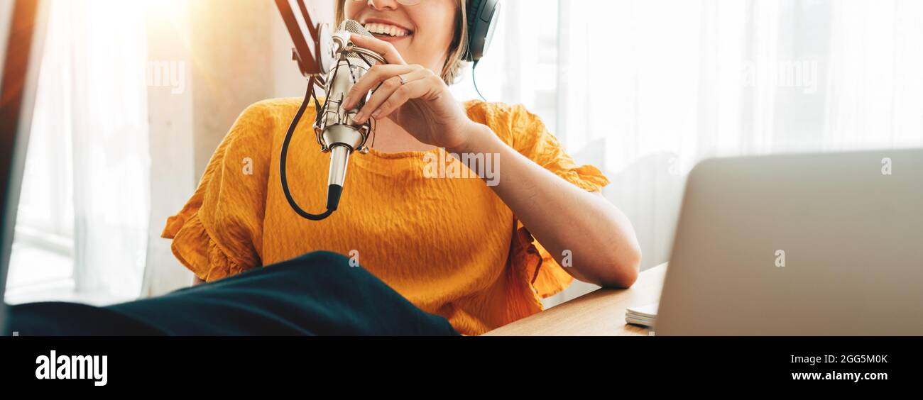 Woman radio host sits with his feet up on his desk and recording audio ...