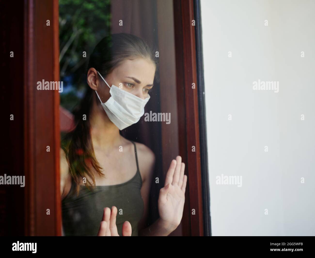 masked woman looking out the window lockdown sadness Stock Photo - Alamy