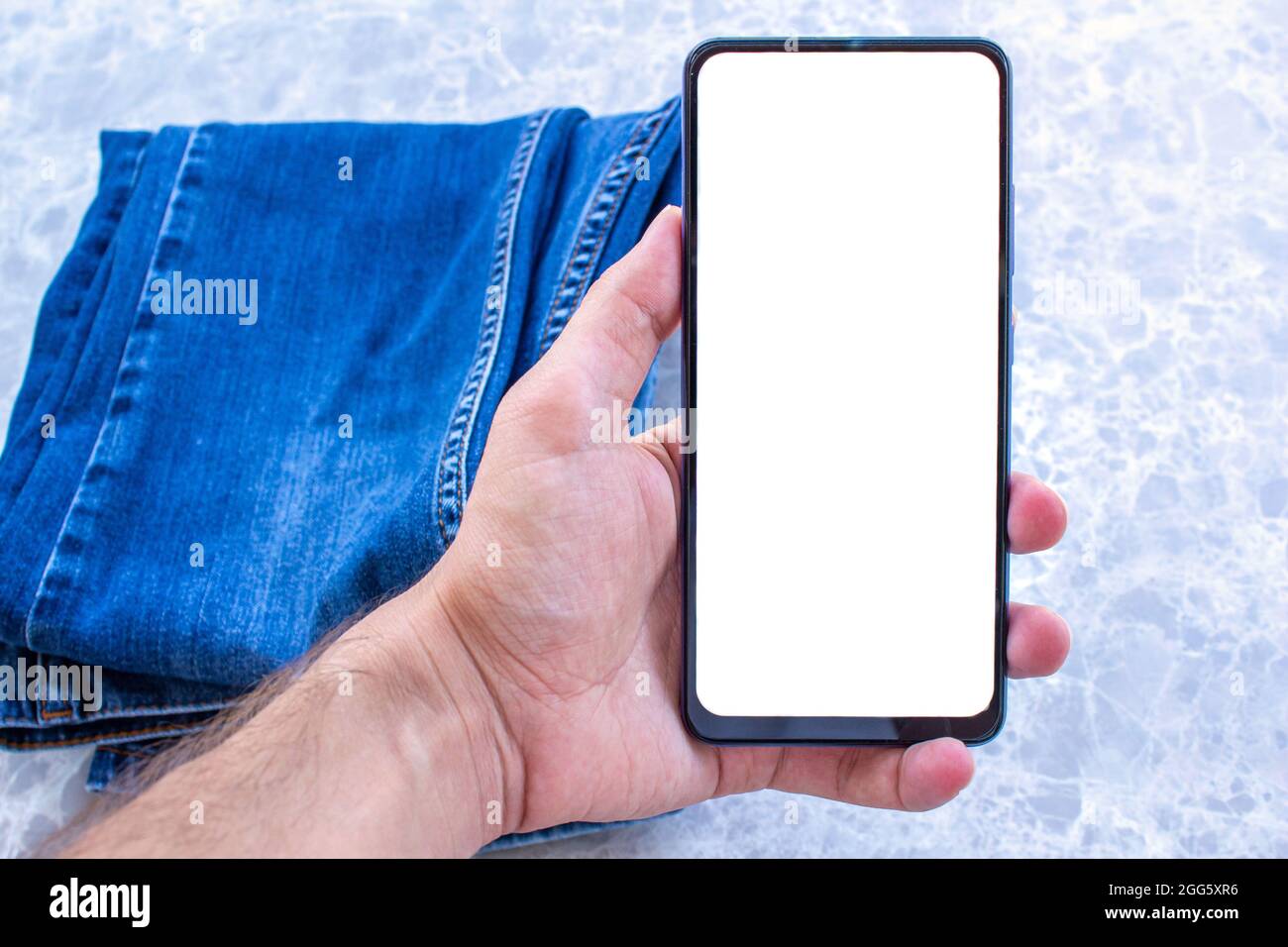 Man hand holding white desktop screen mobile phone. Blue denim jean in ...