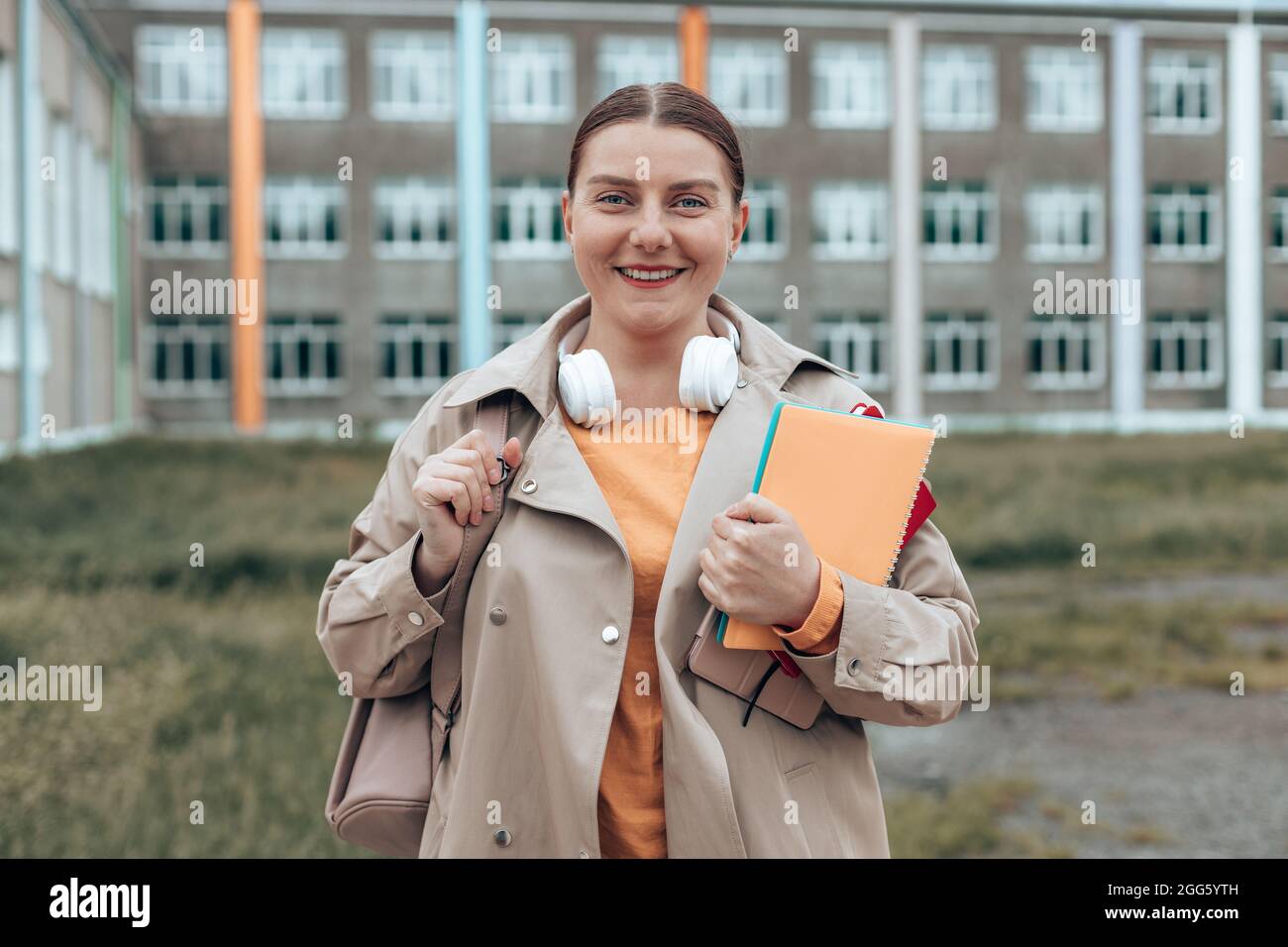 Young girl student with books and notebooks in hand, stands near the ...