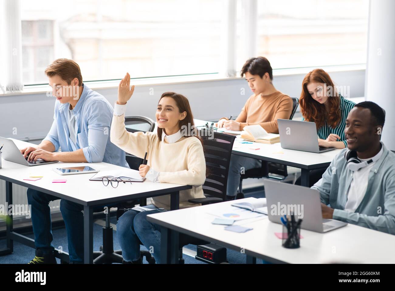 Portrait of smiling female student raising hand at classroom Stock ...