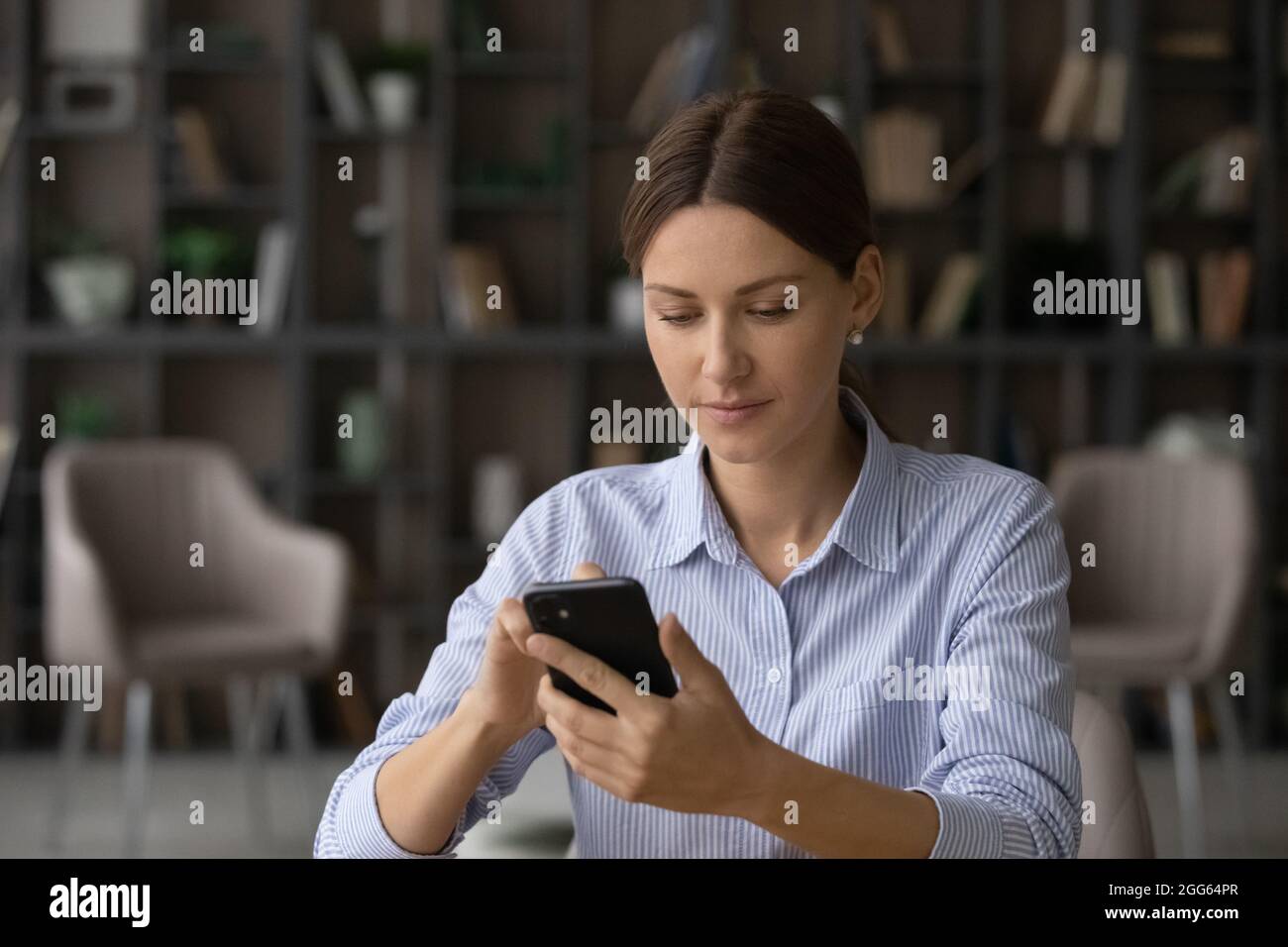 Focused businesswoman looking at phone screen, browsing mobile device ...