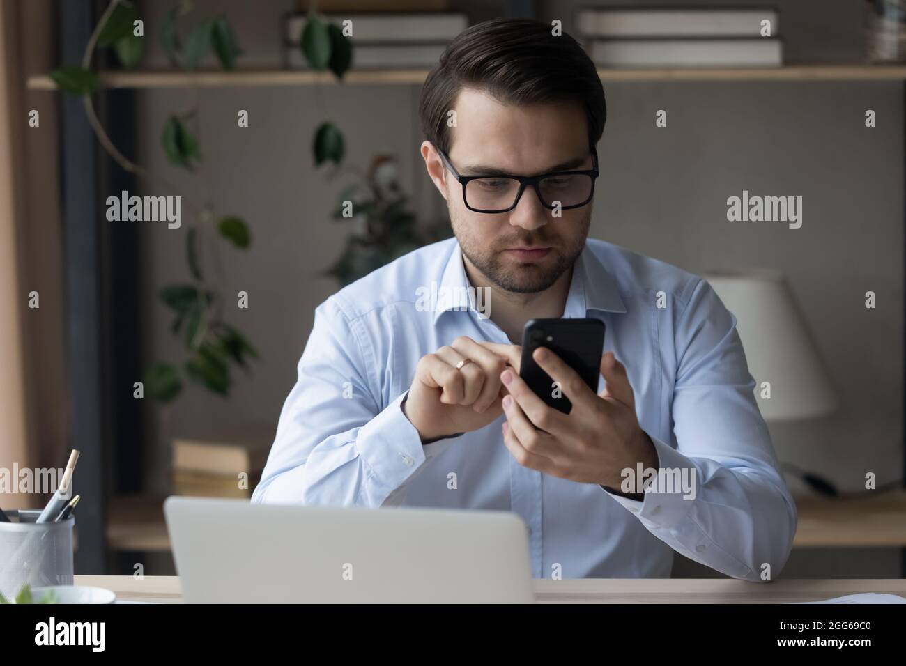 Focused businessman using smartphone at workplace, reading text message ...