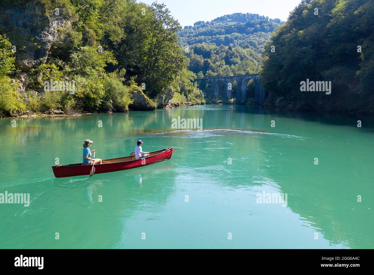 Aerial view of mother and son rowing in a red canoe on Soca river under ...