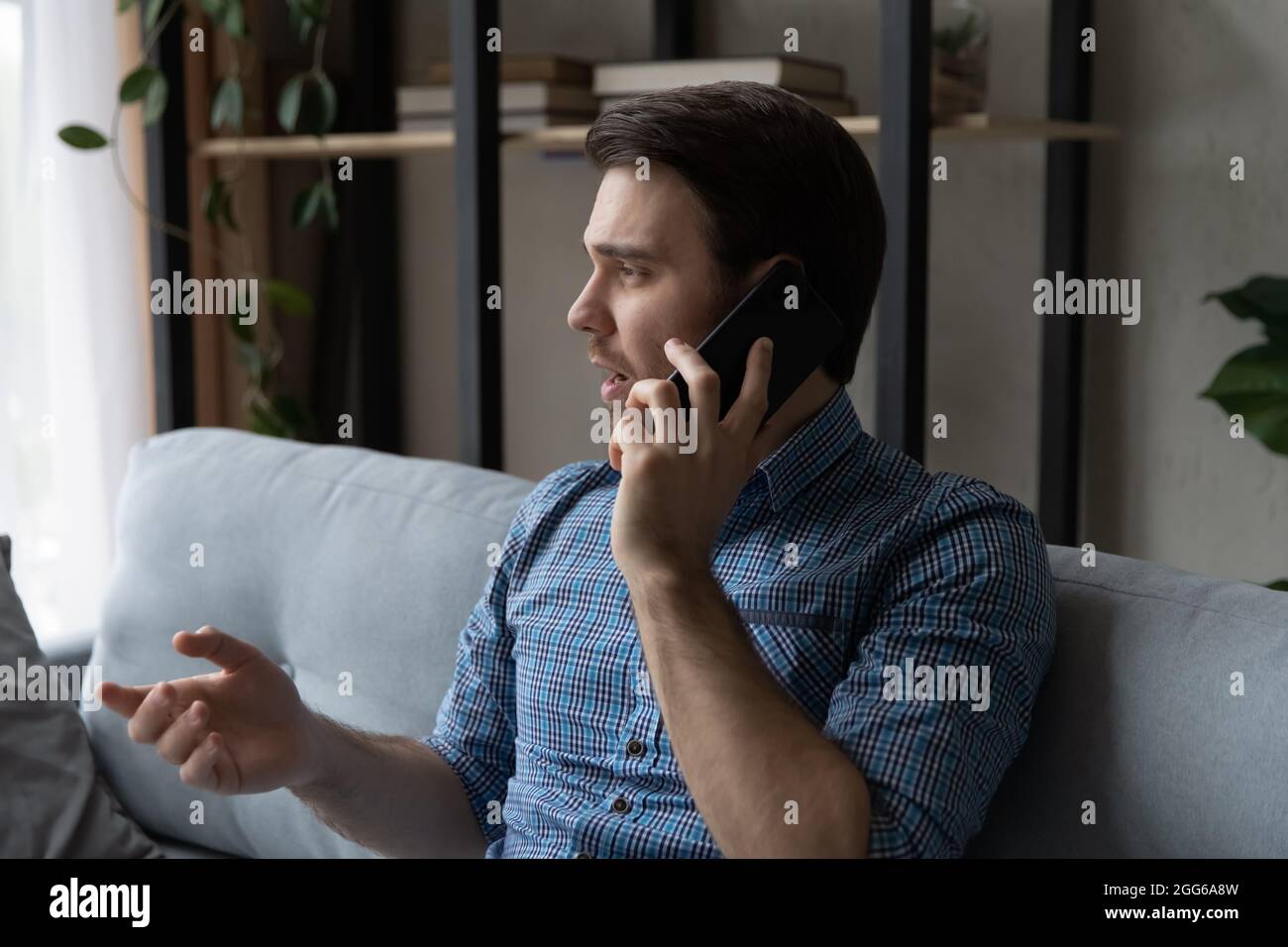 Serious thoughtful mobile phone user making telephone call from home ...