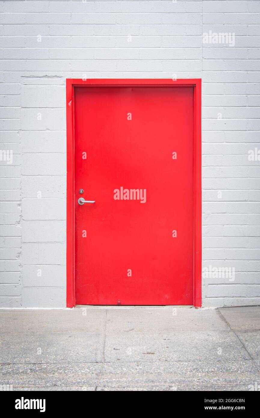 Bright red door in white brick wall Stock Photo - Alamy