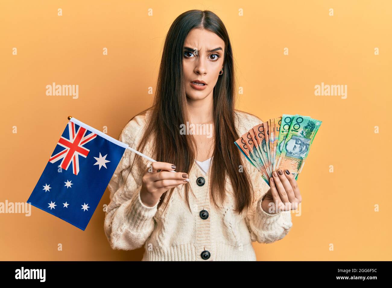 Beautiful brunette young woman holding australian flag and dollars in ...