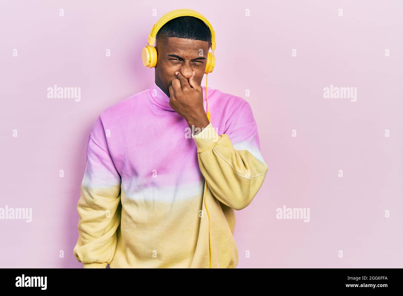 Young black man listening to music wearing headphones smelling ...