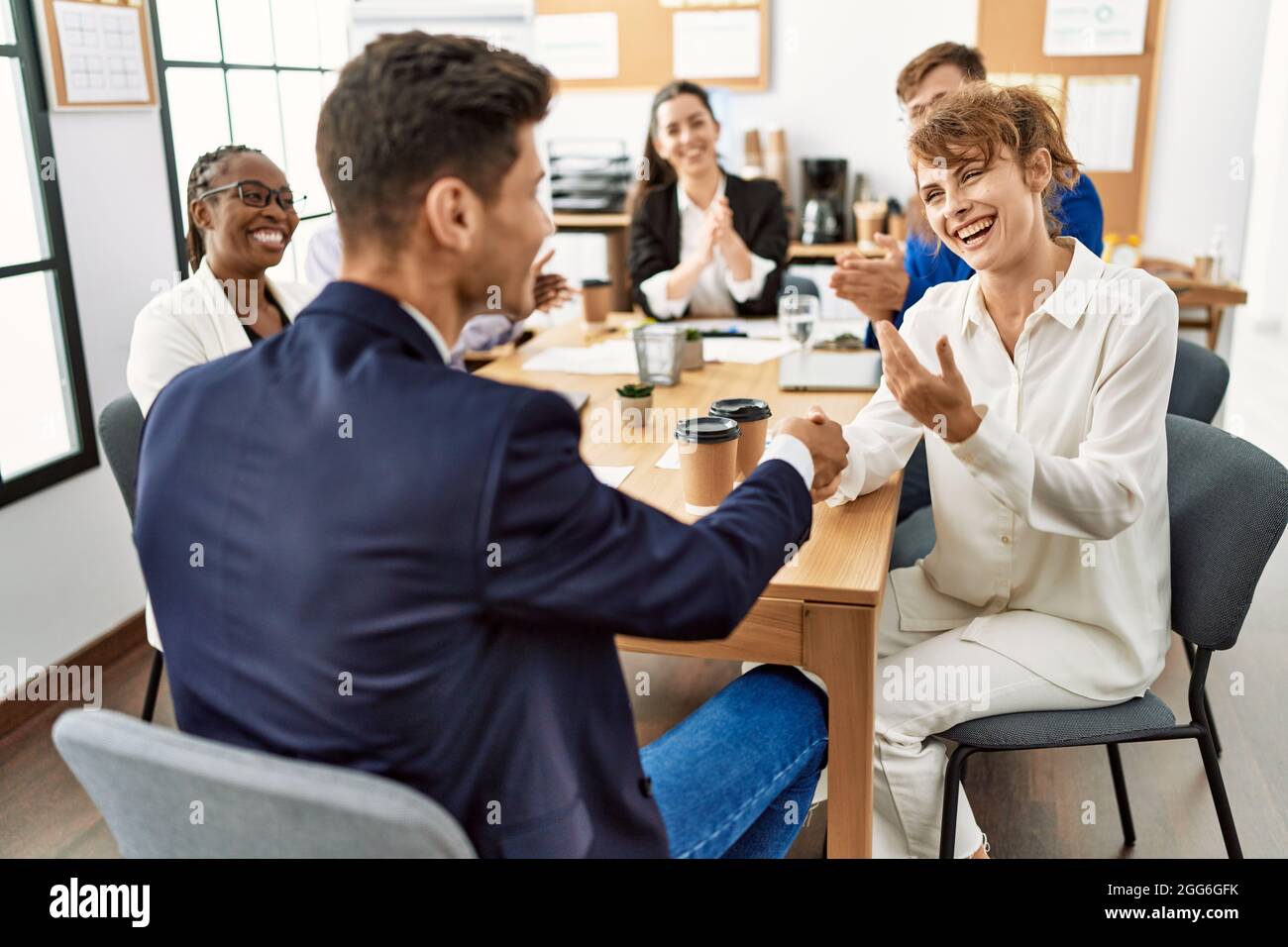 Group of business workers smiling and clapping to partners handshake at ...