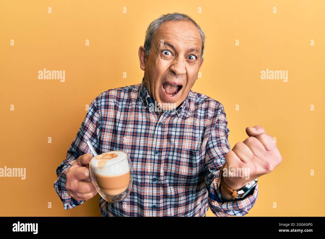 Handsome senior man with grey hair drinking a cup coffee angry and mad ...