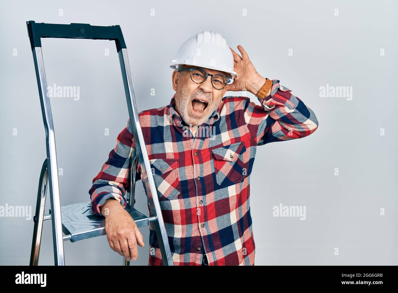 Handsome mature handyman close to construction stairs wearing hardhat ...