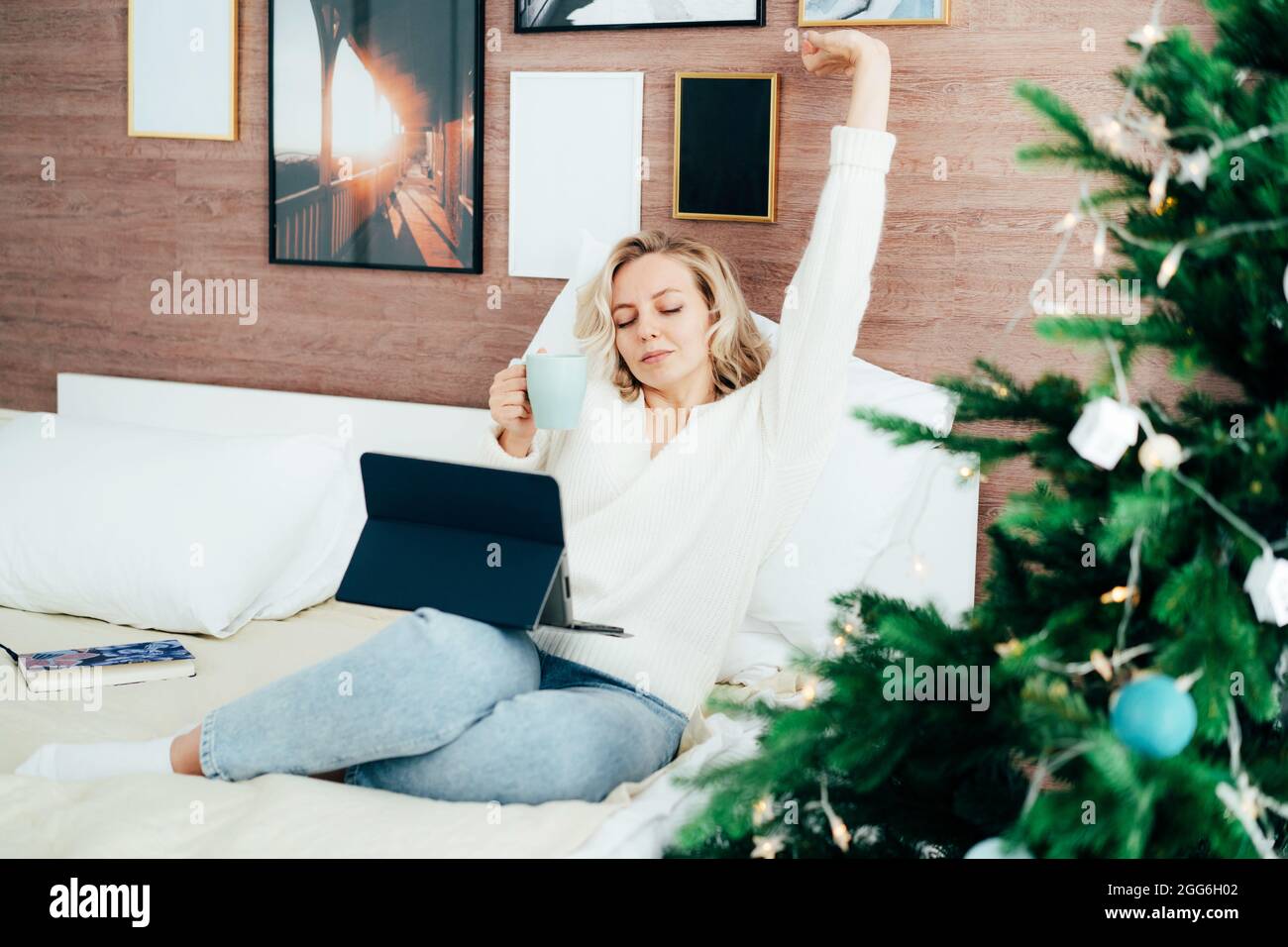 Young attractive business woman stretches lazily while sitting on bed ...