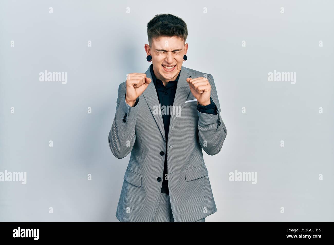 Young caucasian boy with ears dilation wearing business jacket excited ...