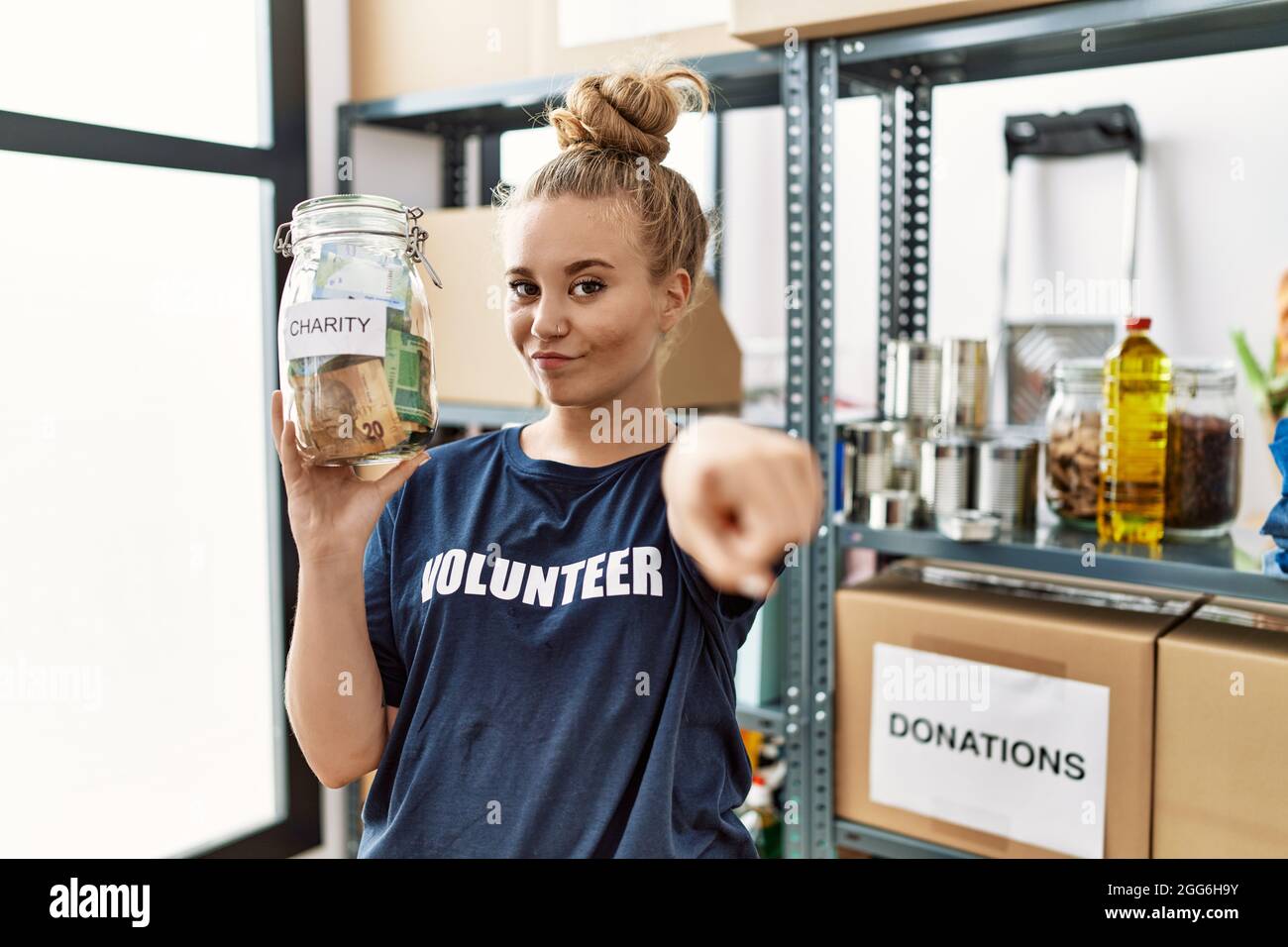 Young caucasian woman holding charity jar with money at donations stand ...