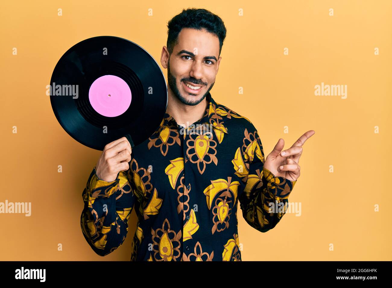 Young hispanic man holding vinyl disc smiling happy pointing with hand ...