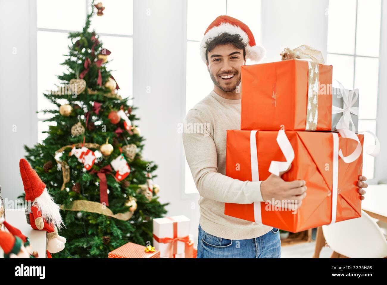 Young hispanic man smiling happy holding gifts at home Stock Photo - Alamy