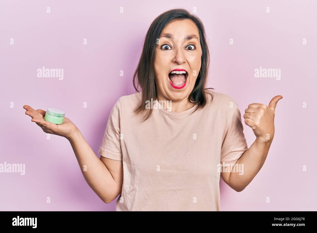 Middle age hispanic woman holding cosmetic moisturizer facial cream ...